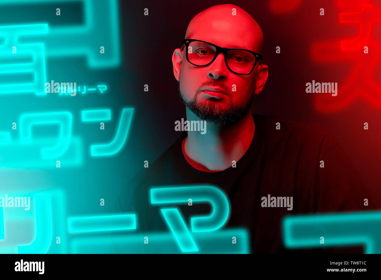 Attractive bald man with beard in glasses on black neon light ...