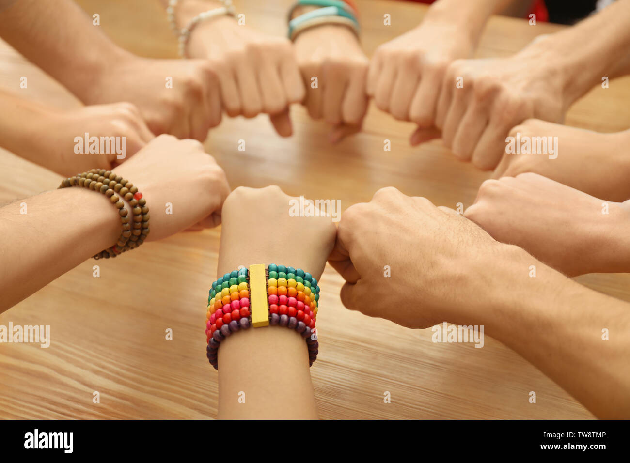 Group of people putting hands together over wooden table as symbol of ...