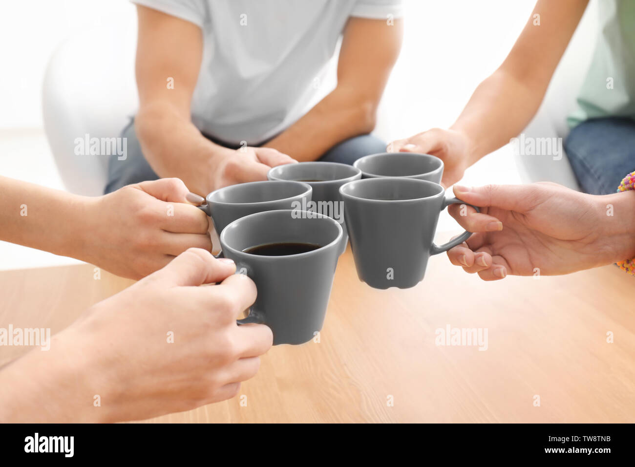 People putting cups of coffee together over wooden table. Unity concept ...