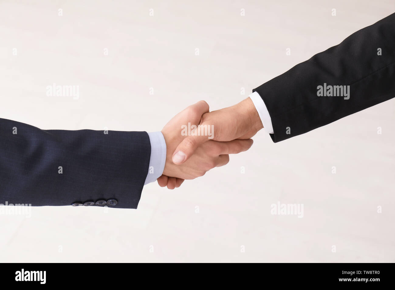 Two man shaking hands as symbol of unity on light background Stock ...