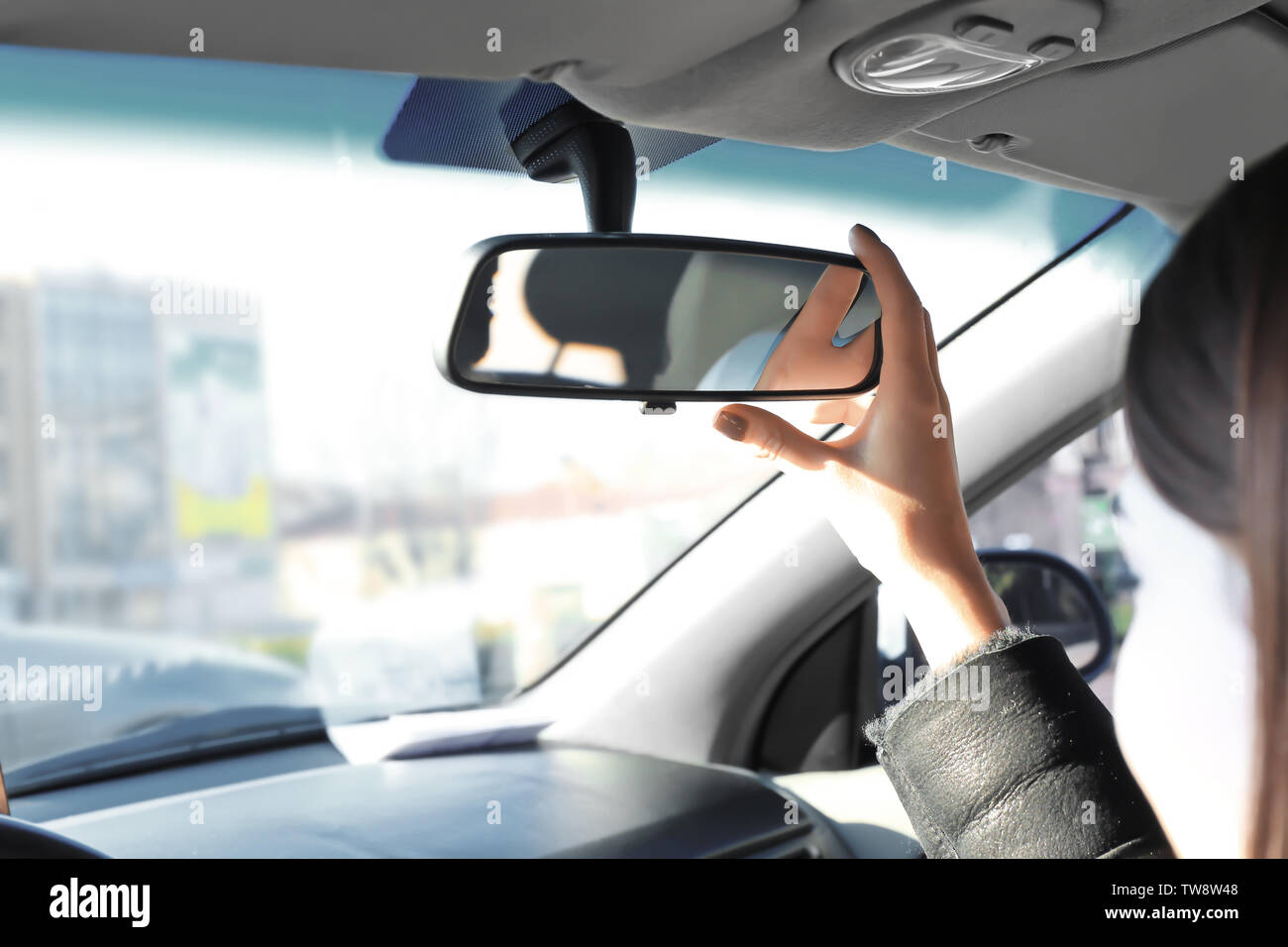 Woman adjusting rear view mirror in car Stock Photo - Alamy