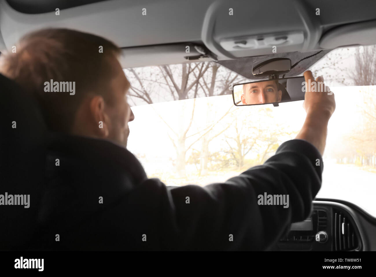 Man adjusting rear view mirror in car Stock Photo - Alamy