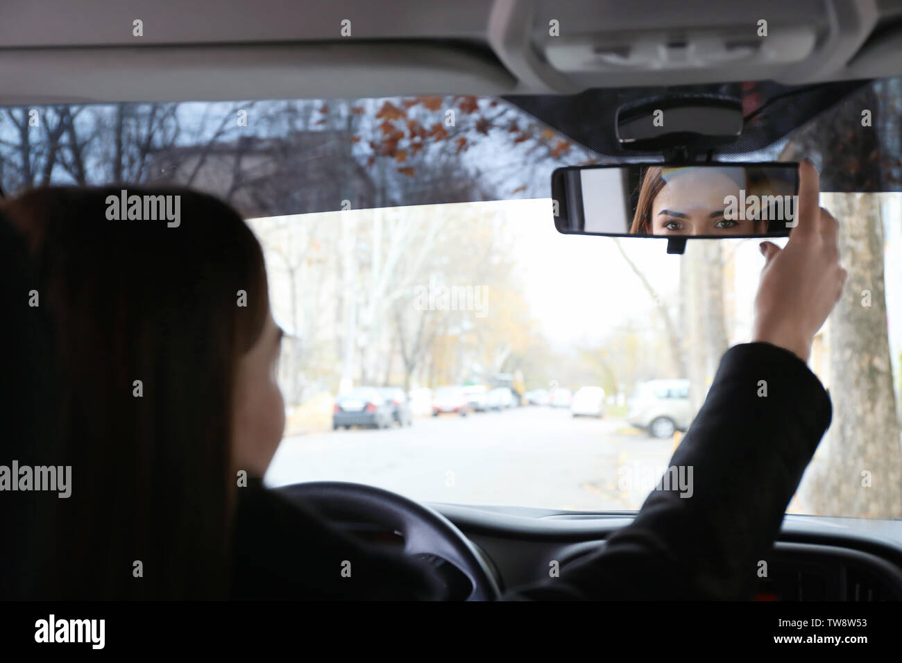Woman adjusting rear view mirror in car Stock Photo - Alamy