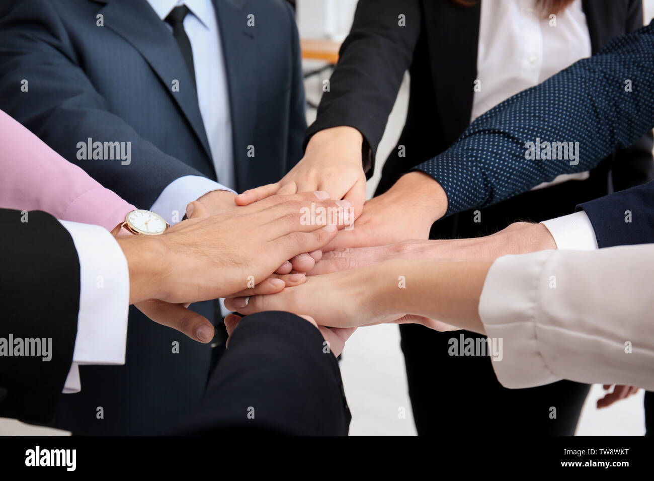 People putting hands together indoors. Unity concept Stock Photo - Alamy