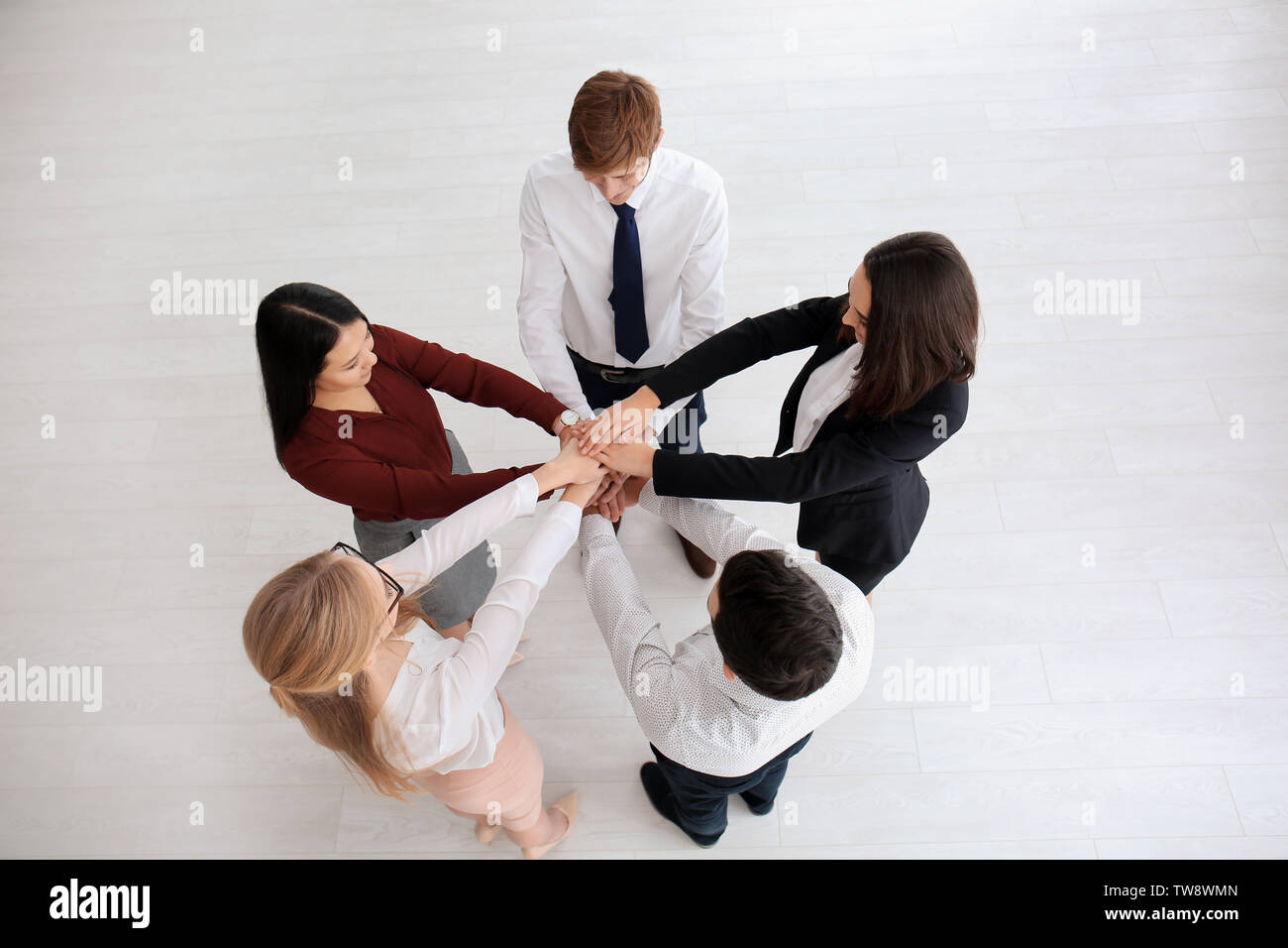 People putting hands together indoors. Unity concept Stock Photo - Alamy