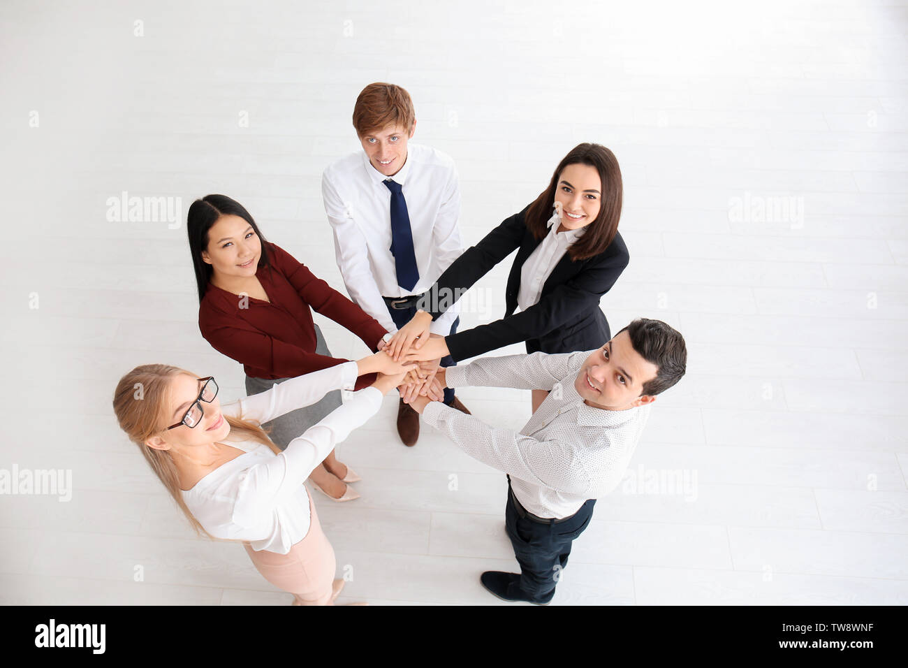 People putting hands together indoors. Unity concept Stock Photo - Alamy