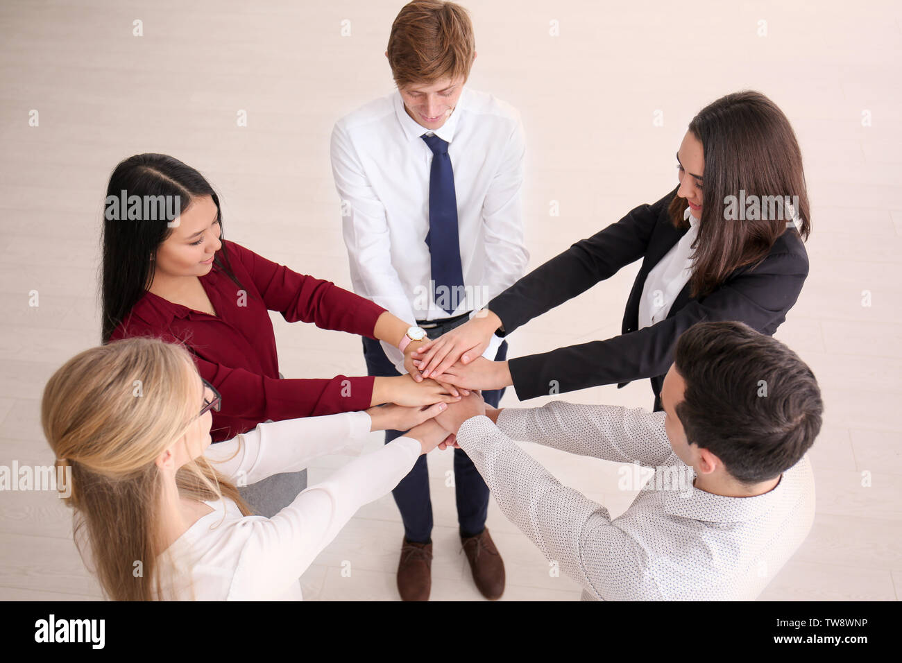 People putting hands together indoors. Unity concept Stock Photo - Alamy