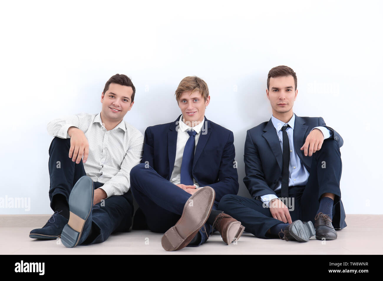 Men sitting together near white wall. Unity concept Stock Photo - Alamy