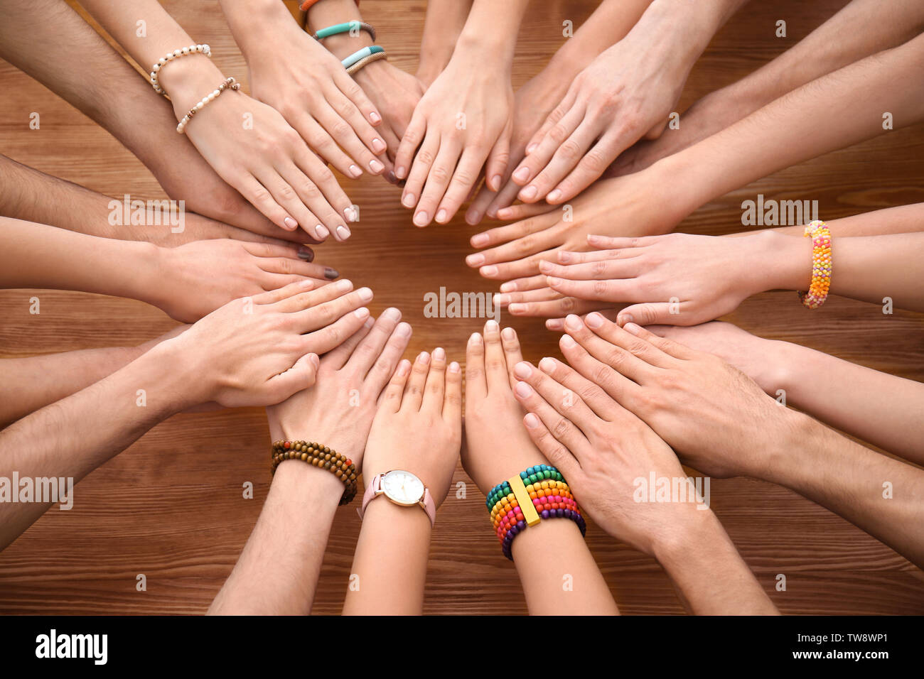 People putting hands together at wooden table as symbol of unity Stock ...