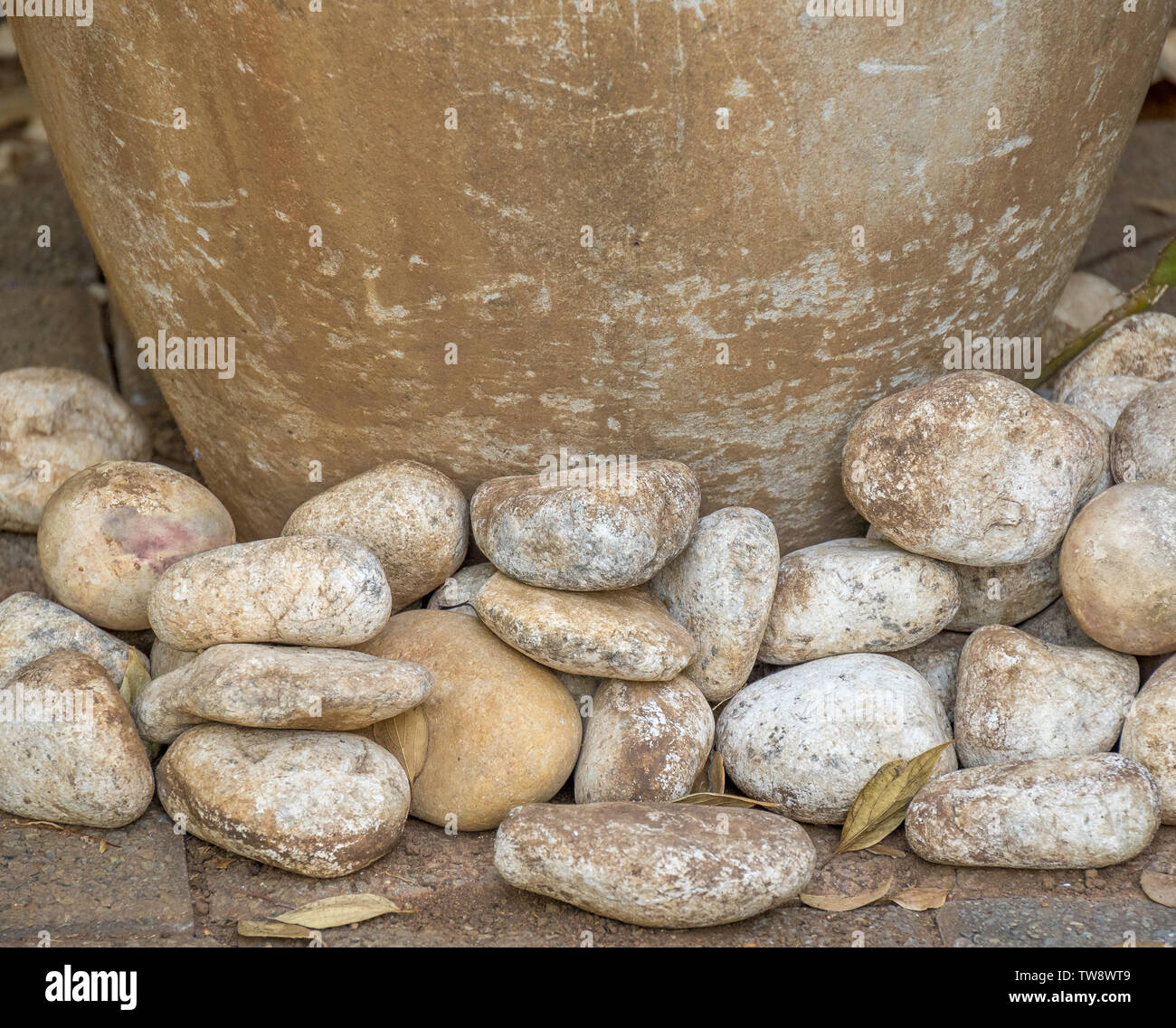Dirty white stones isolated at the base of an outdoor plant container ...