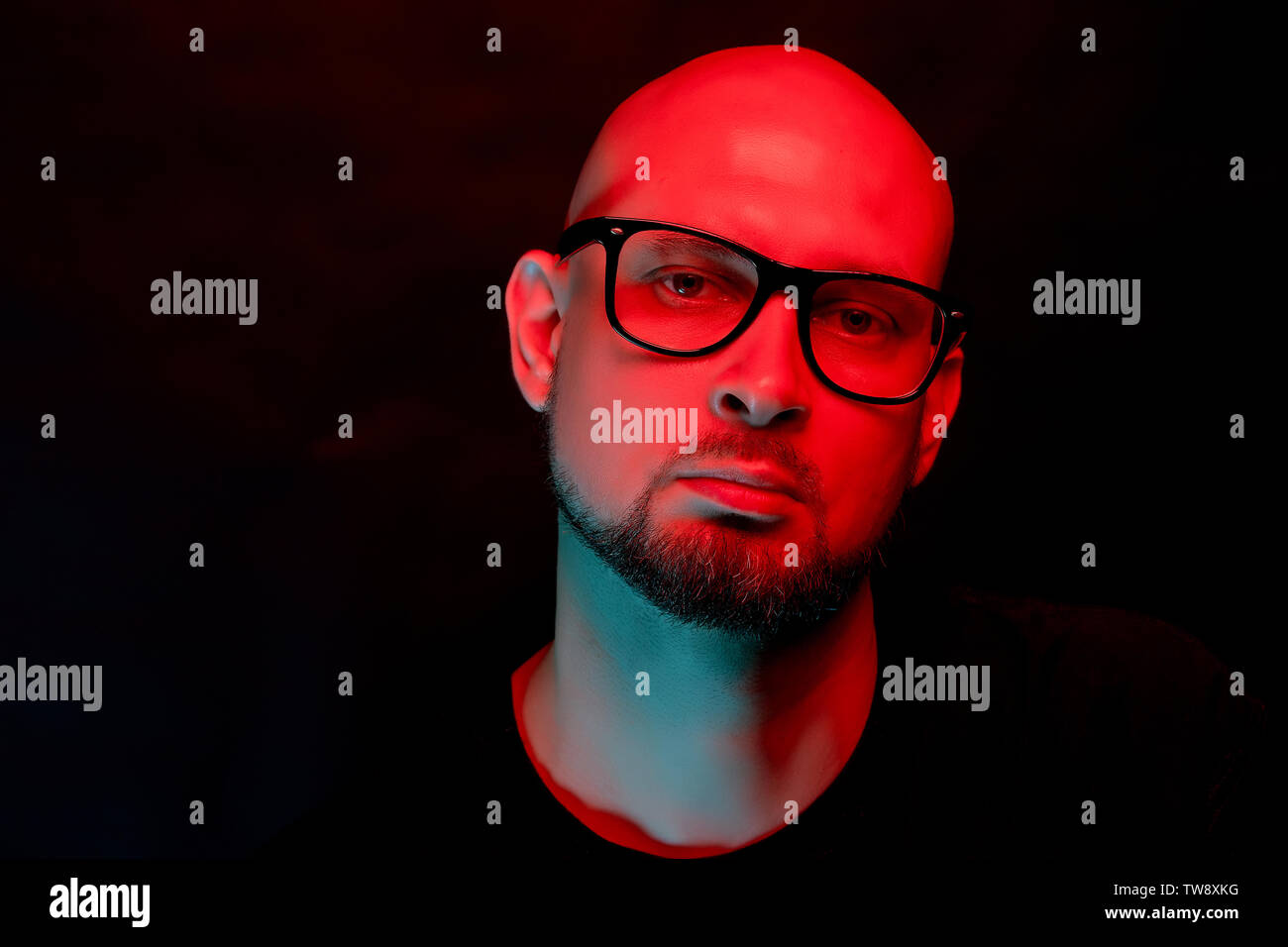 Attractive bald man with beard in glasses on neon light background ...