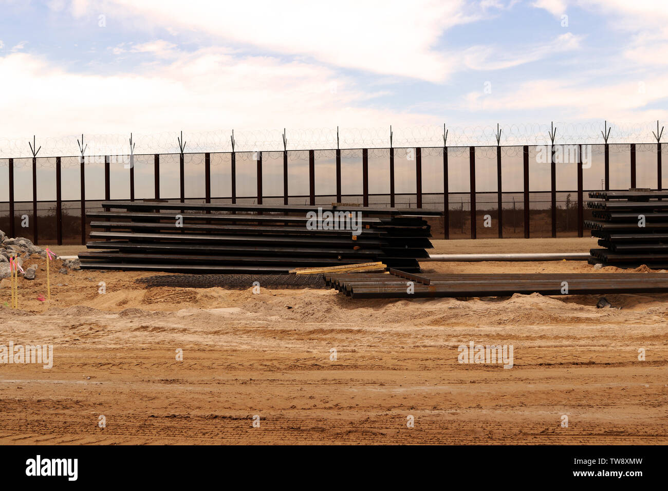 Looking north at existing border barrier. Stacks of new steel bollard ...