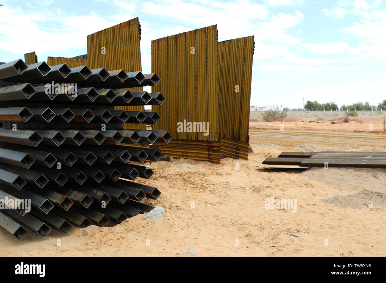 Looking north at existing border barrier. Stacks of new steel bollard ...