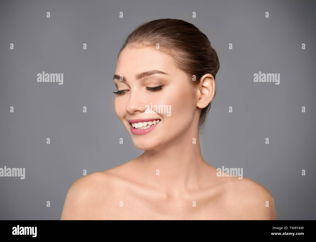Portrait of beautiful young woman with clear skin on grey background ...
