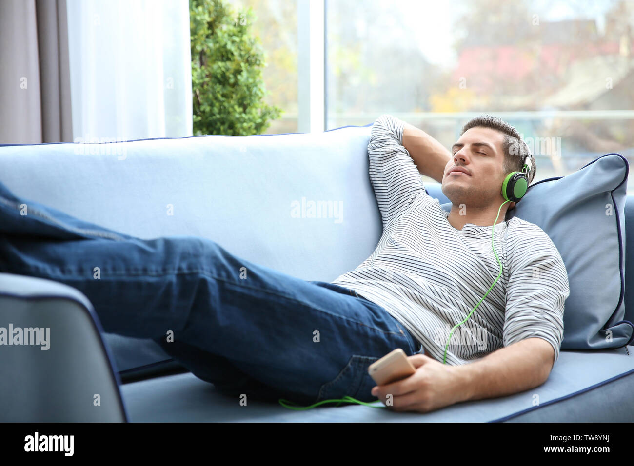 Relaxed young man listening to music at home Stock Photo - Alamy