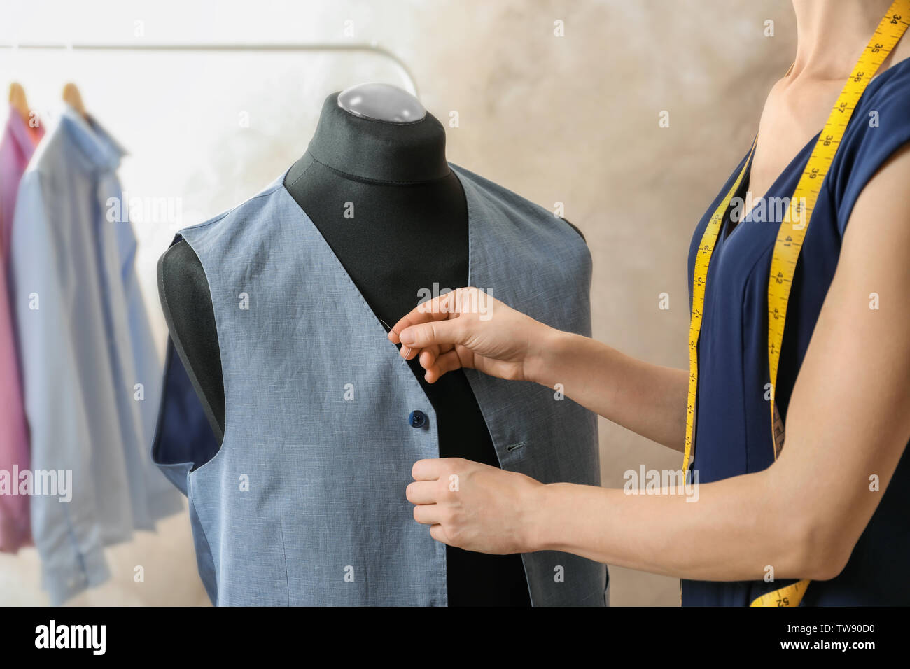 Seamstress tailoring vest on mannequin in workshop Stock Photo - Alamy