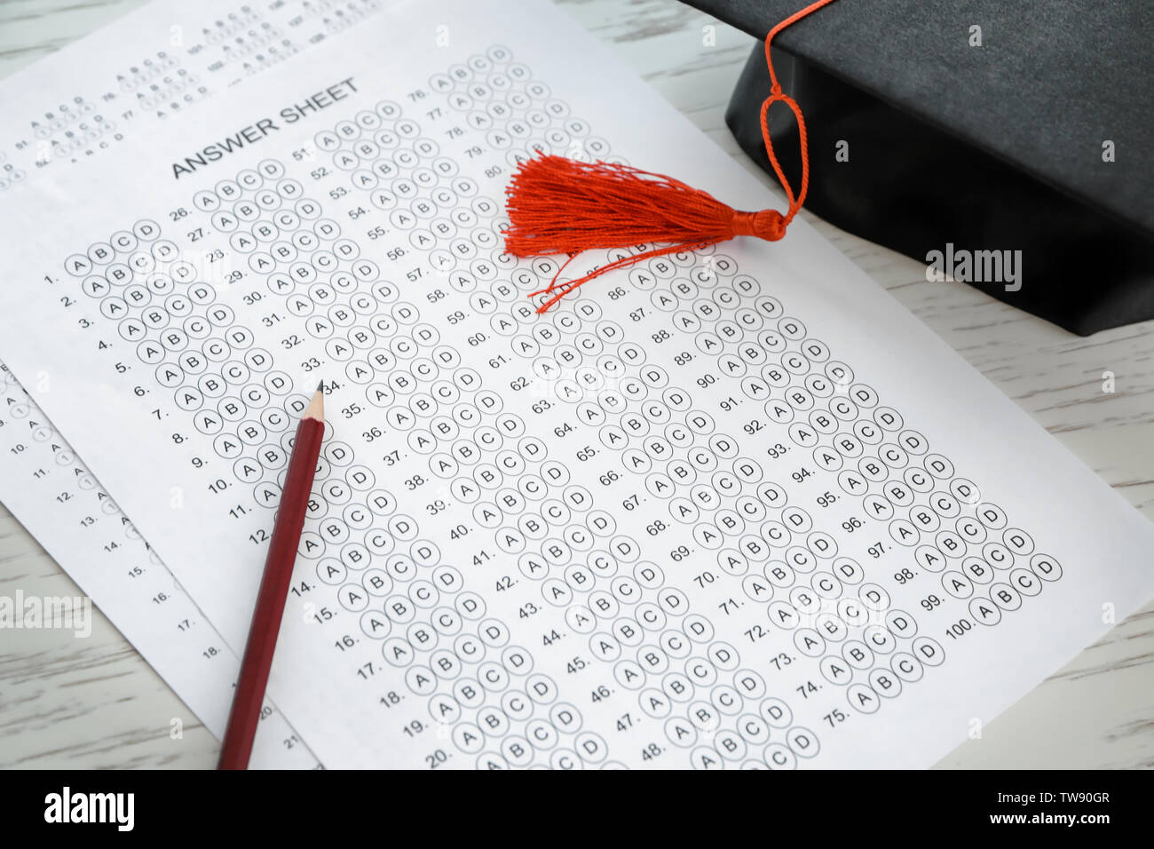 Answer sheets with pencil and graduation cap on table. Passing of exams ...