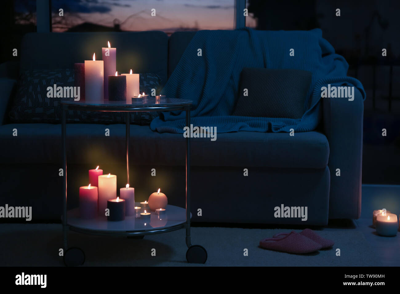 Burning candles on table in dark room Stock Photo - Alamy