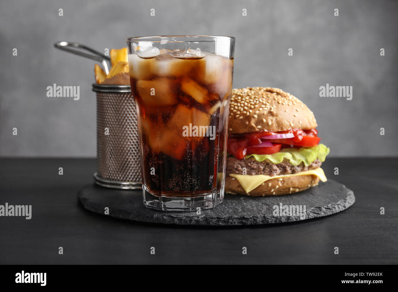Glass of cold cola with tasty burger on slate plate Stock Photo - Alamy