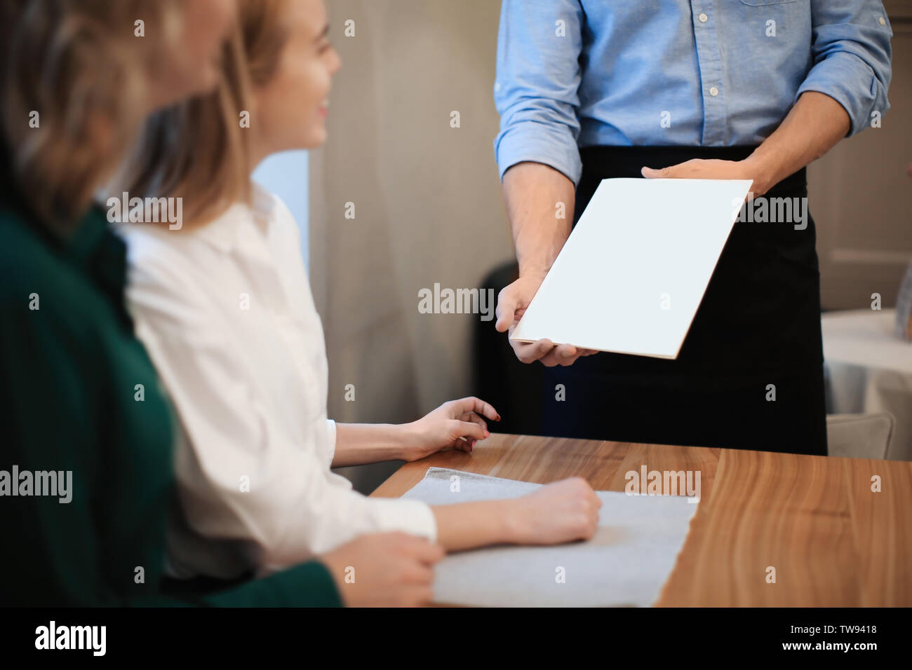Waiter giving menu to customers in cafe Stock Photo - Alamy
