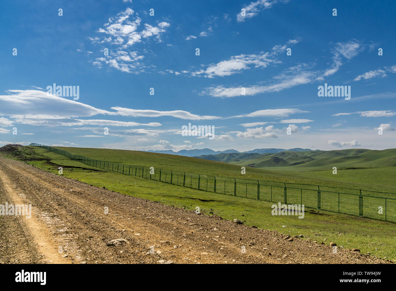Blue sky and white clouds under hillside prairie sand and gravel ground ...