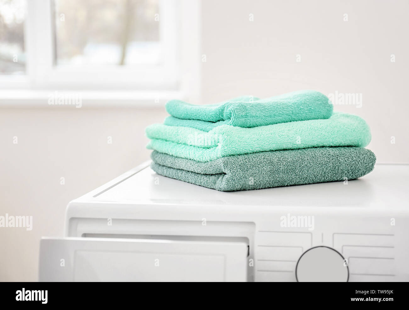 Stack of clean towels on washing machine in laundromat Stock Photo - Alamy