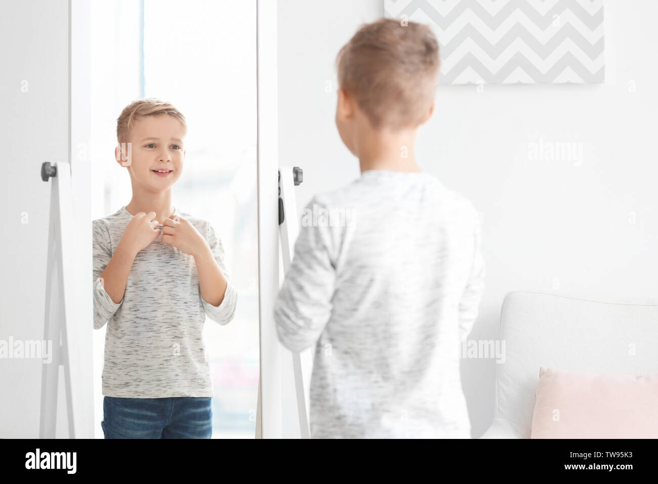 Cute little boy looking at himself in mirror indoors Stock Photo - Alamy