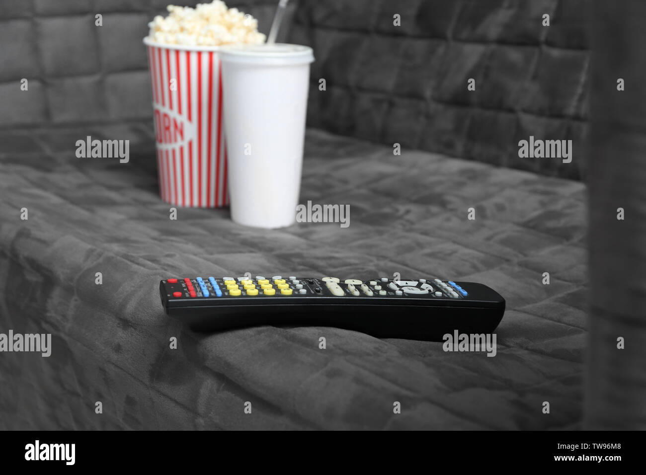 Comfortable sofa with TV remote control and snack, closeup. Home cinema ...