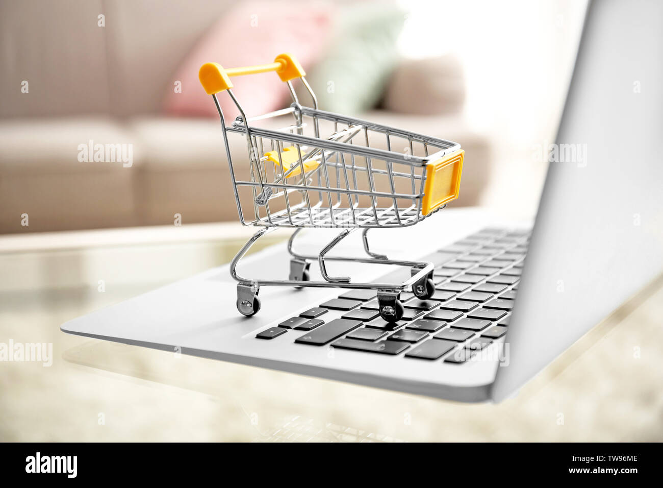 Laptop and small shopping cart on table. Internet shopping concept ...