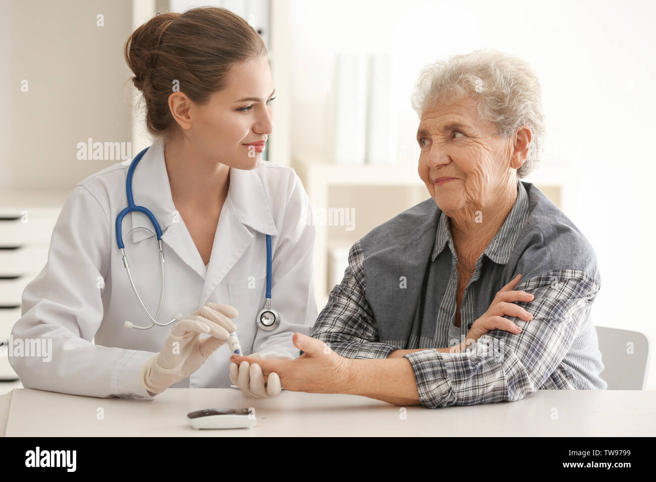Doctor measuring blood sugar level of diabetic patient in clinic Stock ...
