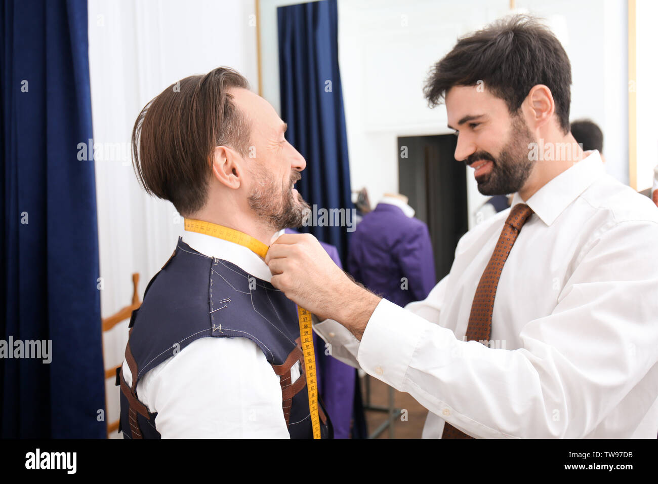 Tailor measuring client for custom made suit in atelier Stock Photo - Alamy