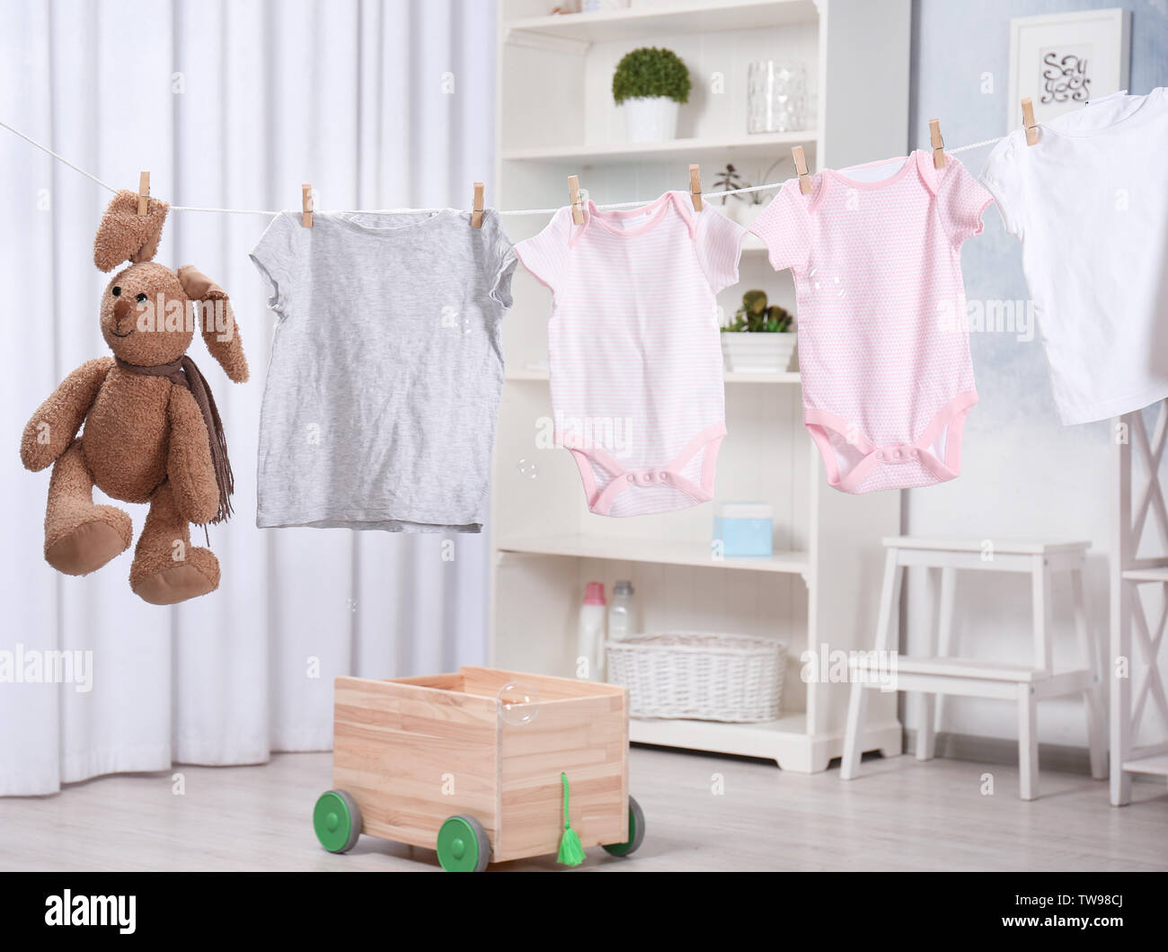 Clothes and toy hanging on laundry line indoors Stock Photo - Alamy