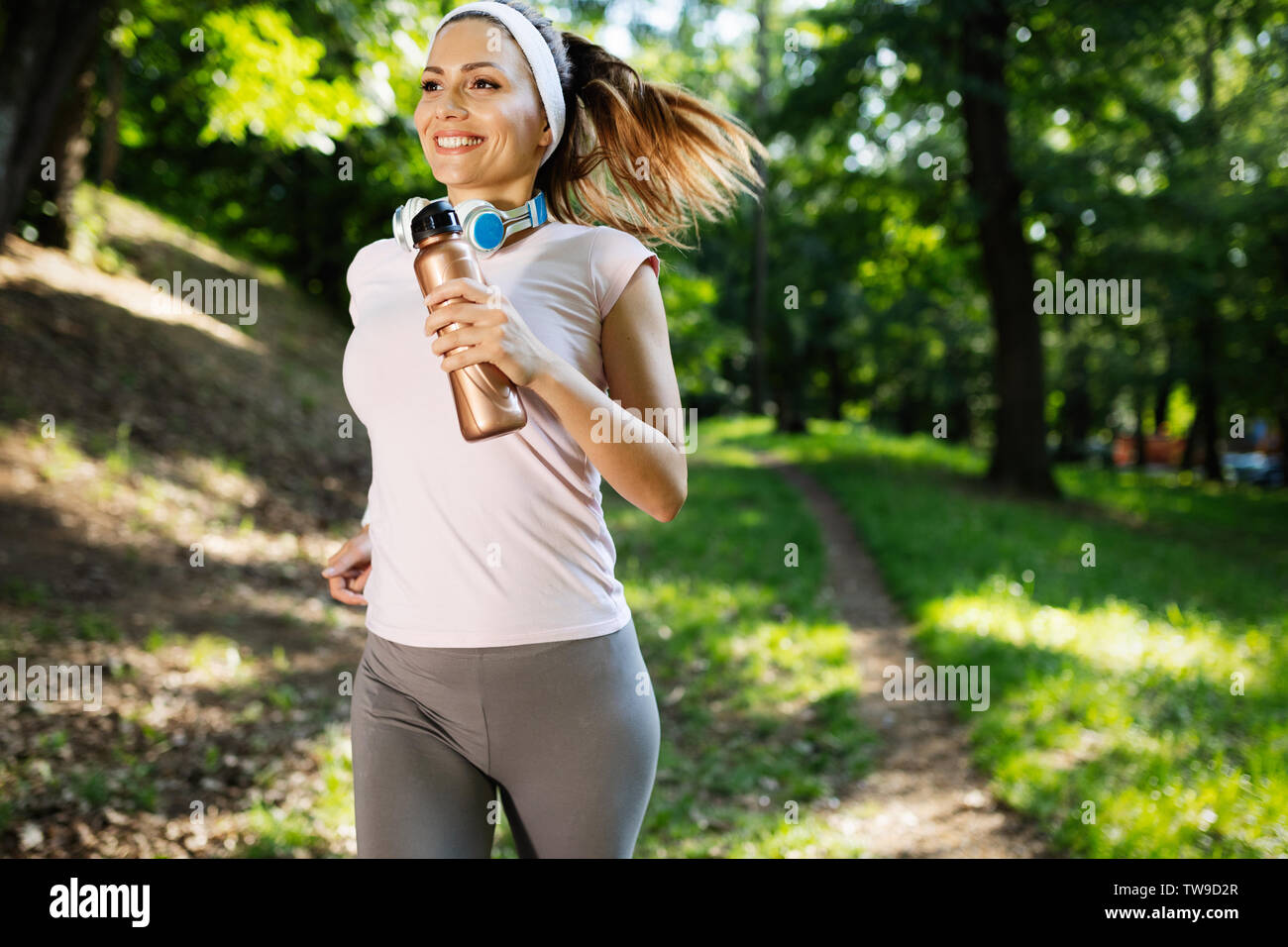 Happy young runner woman runs in the park jogging Stock Photo - Alamy