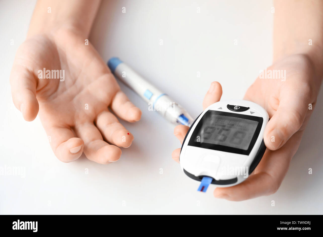 Woman using digital glucometer on light background. Diabetes monitoring ...