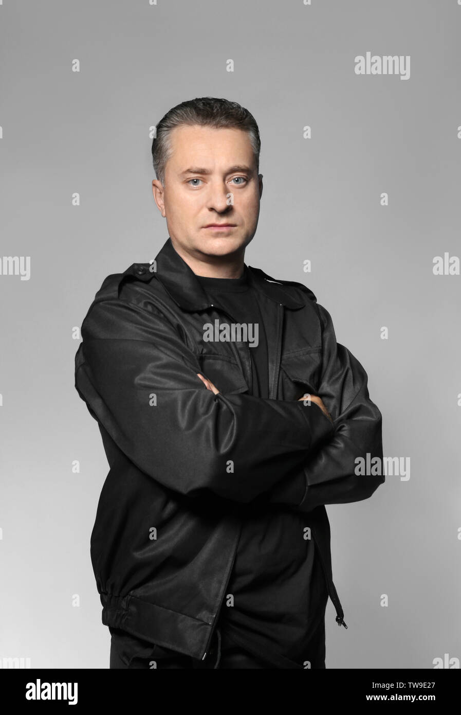 Male security guard on grey background Stock Photo - Alamy
