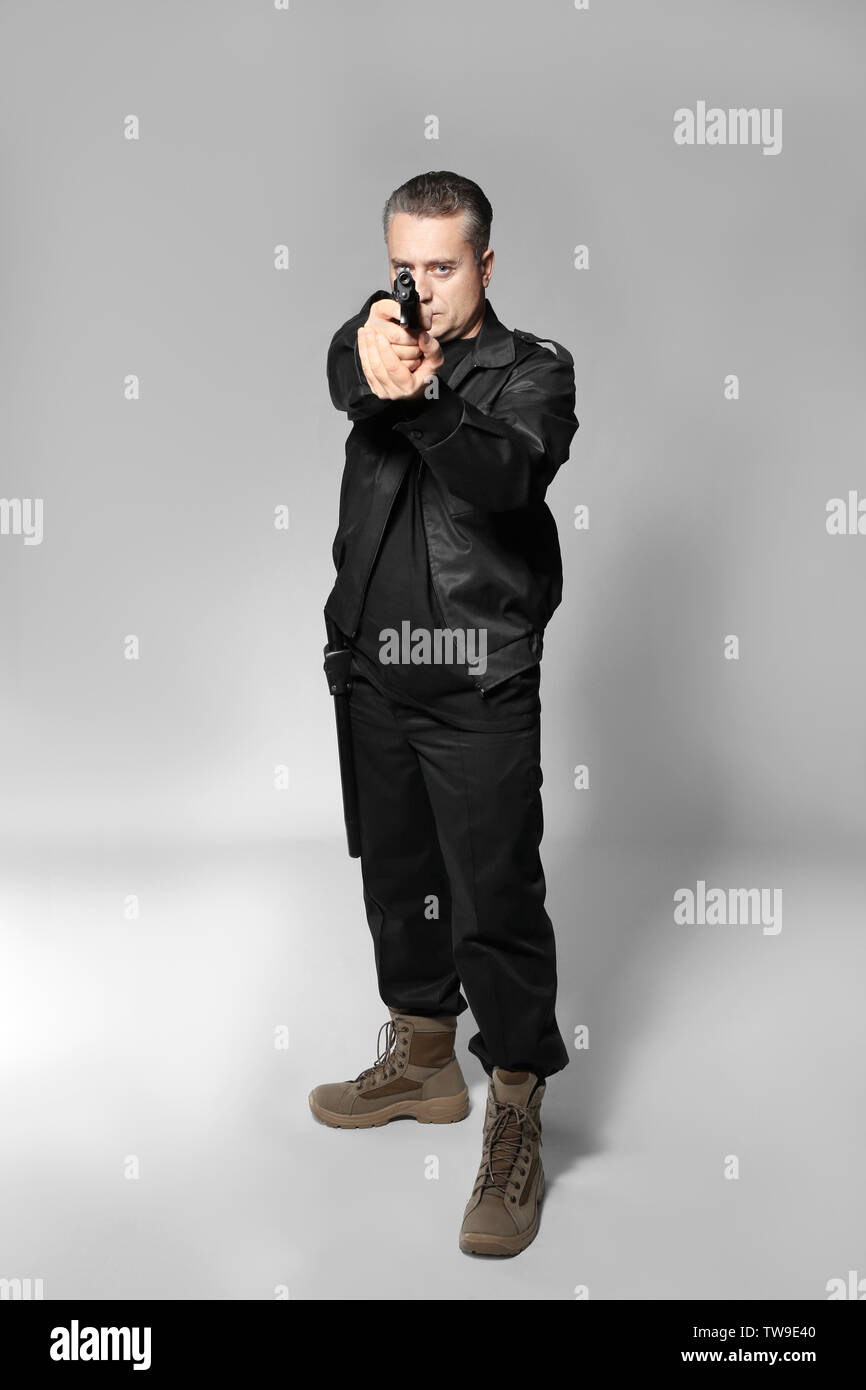 Male security guard with handgun on grey background Stock Photo - Alamy