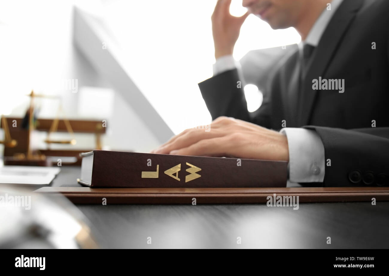 Lawyer holding hand on juridical textbook at table in office Stock ...