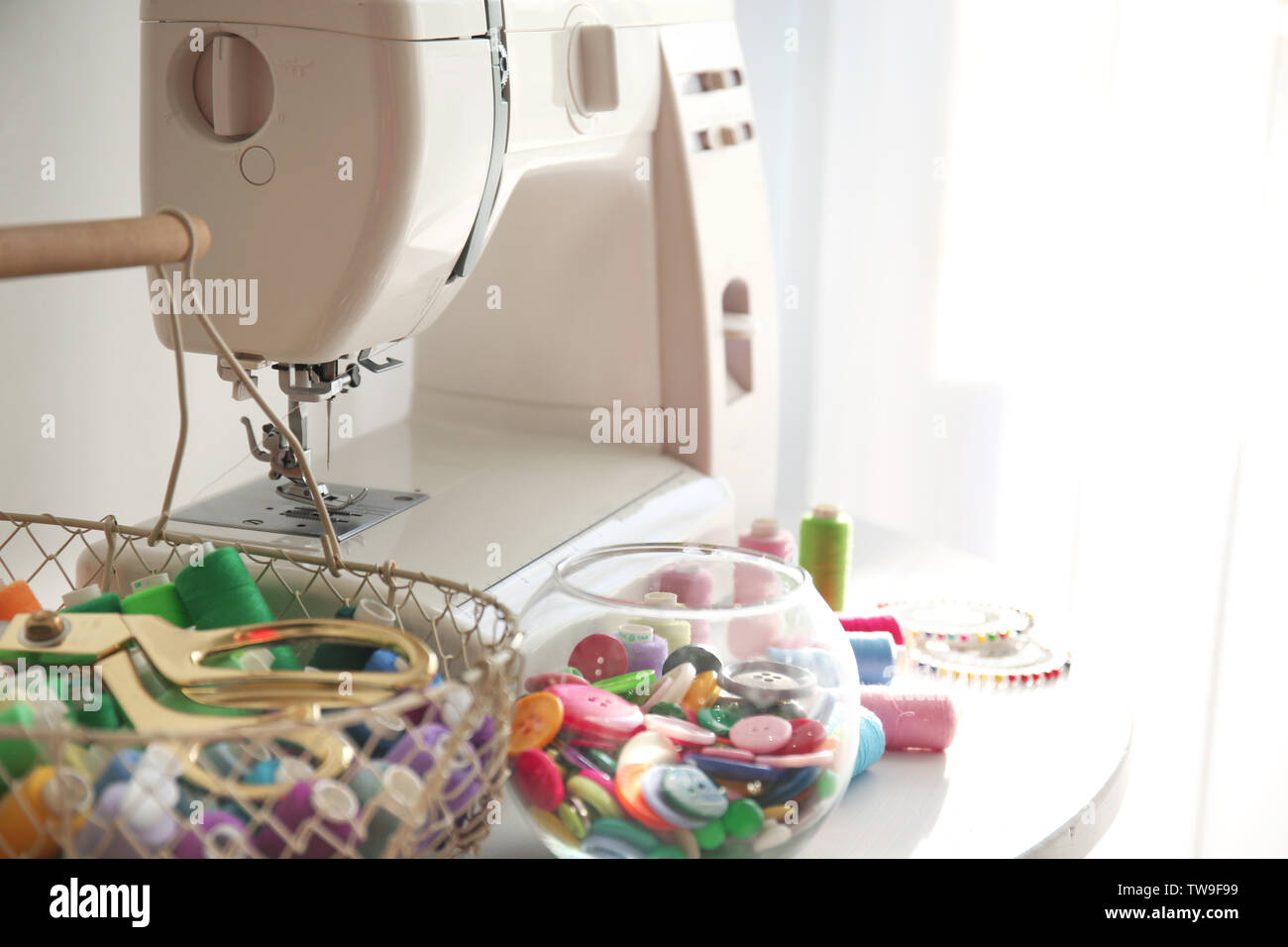 Modern sewing machine with threads on table Stock Photo - Alamy