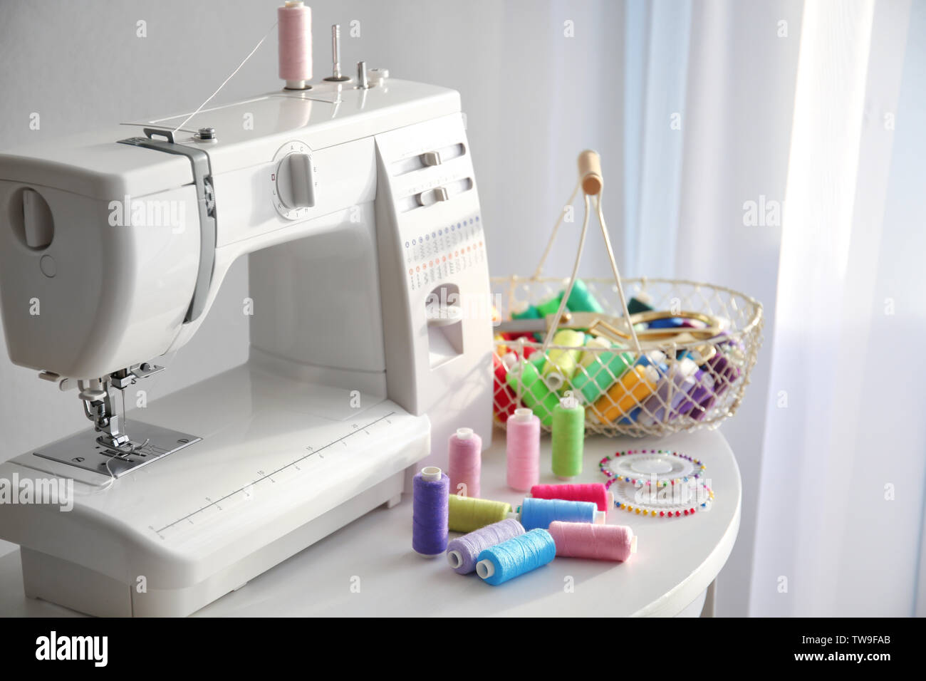 Modern sewing machine with threads on table Stock Photo - Alamy