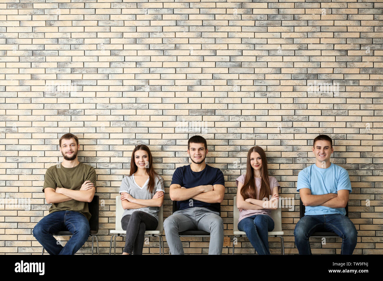 Group of young people sitting on chairs together, indoors. Unity ...