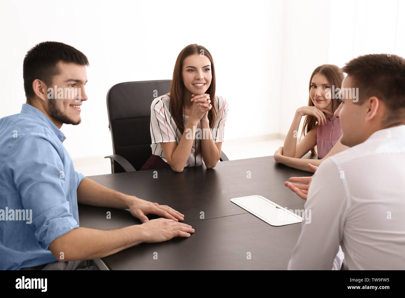 Young people sitting together at table, indoors. Unity concept Stock ...