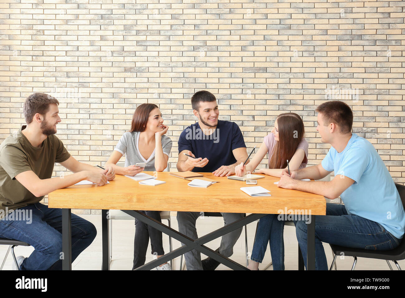 Group of young people sitting at table together, indoors. Unity concept ...