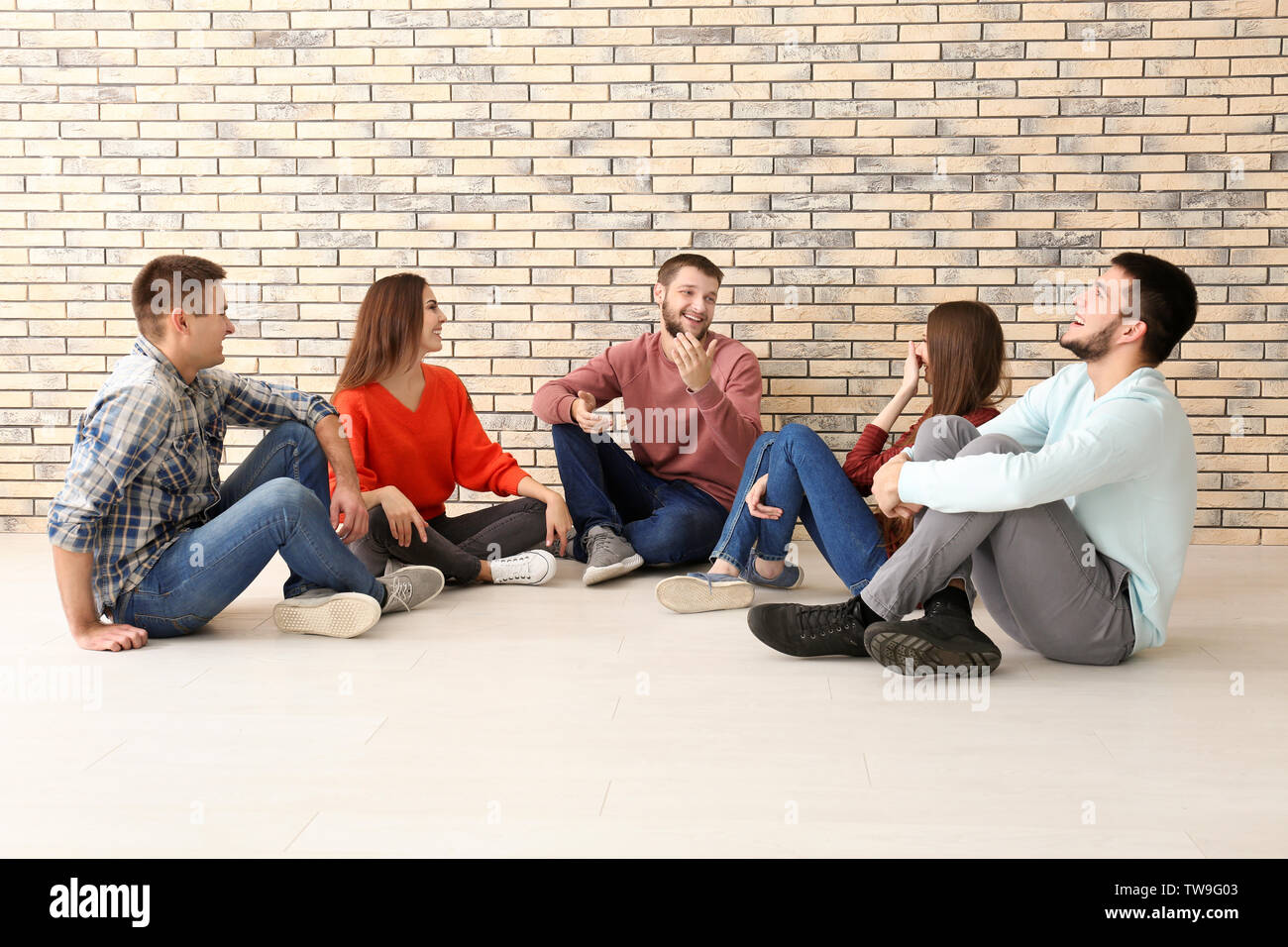 Group of young people sitting on floor together, indoors. Unity concept ...