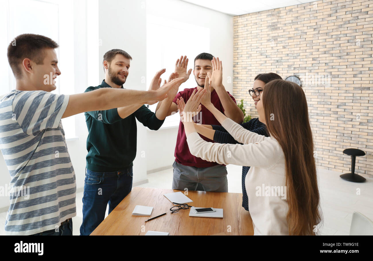 People giving high five over table. Unity concept Stock Photo - Alamy