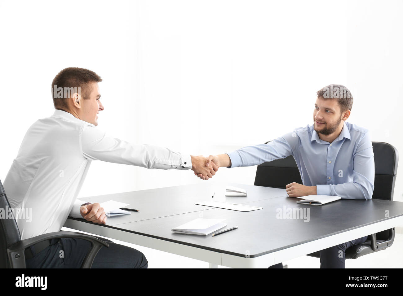 Two young men shaking hands over table, indoors. Unity concept Stock ...