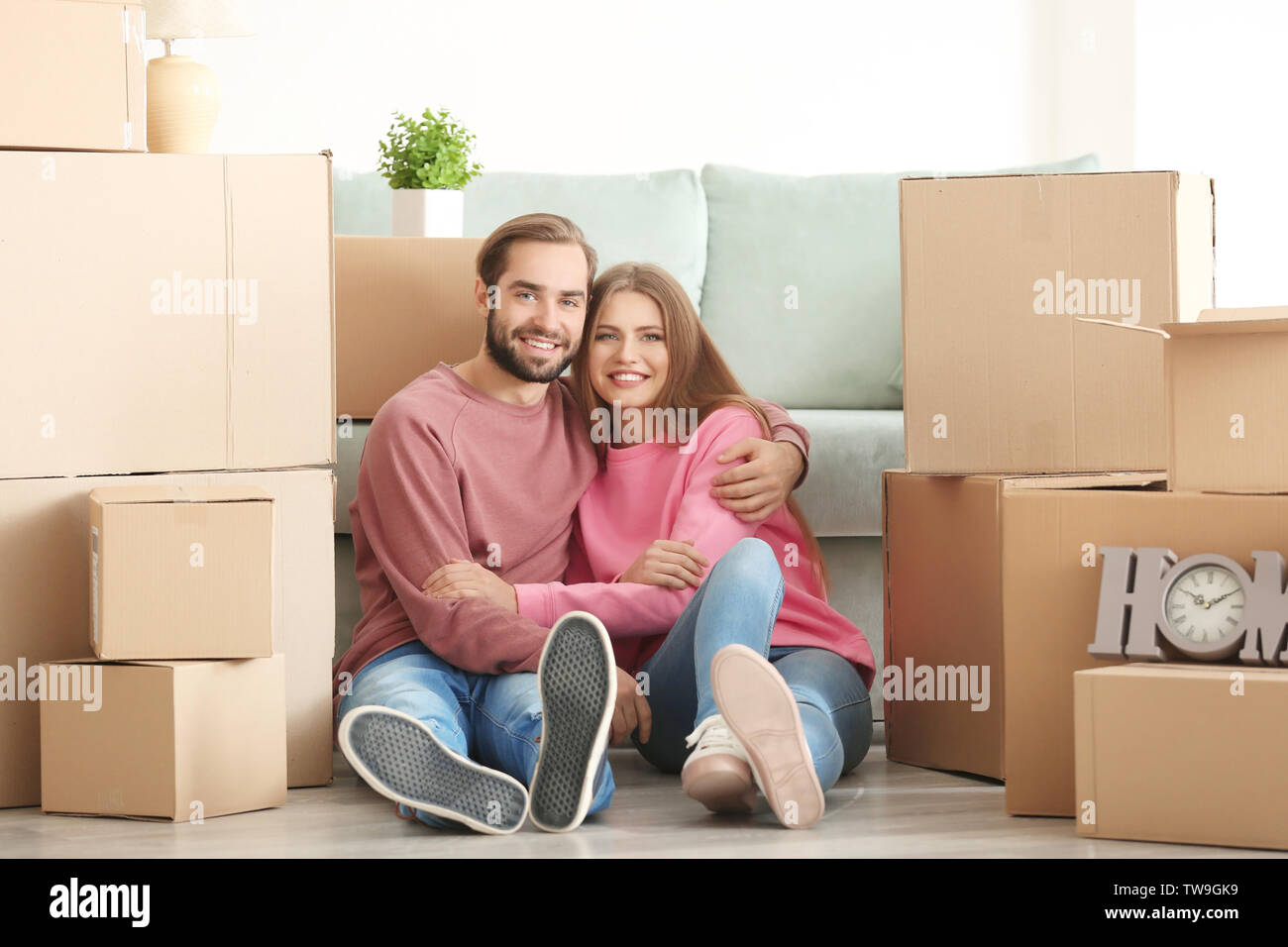 Young couple with moving boxes on floor in room Stock Photo - Alamy