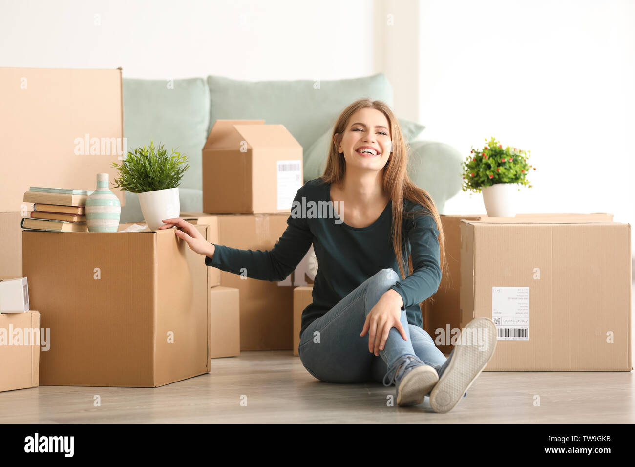 Young woman with moving boxes in room at new home Stock Photo - Alamy