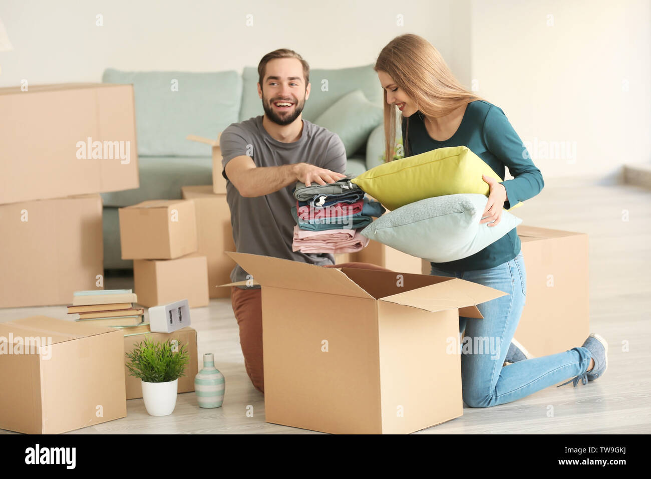 Young couple packing moving boxes in room Stock Photo - Alamy