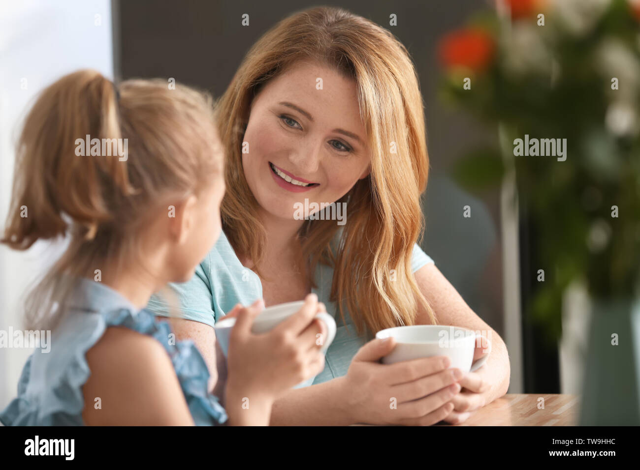 Happy mother and daughter drinking tea in kitchen Stock Photo - Alamy
