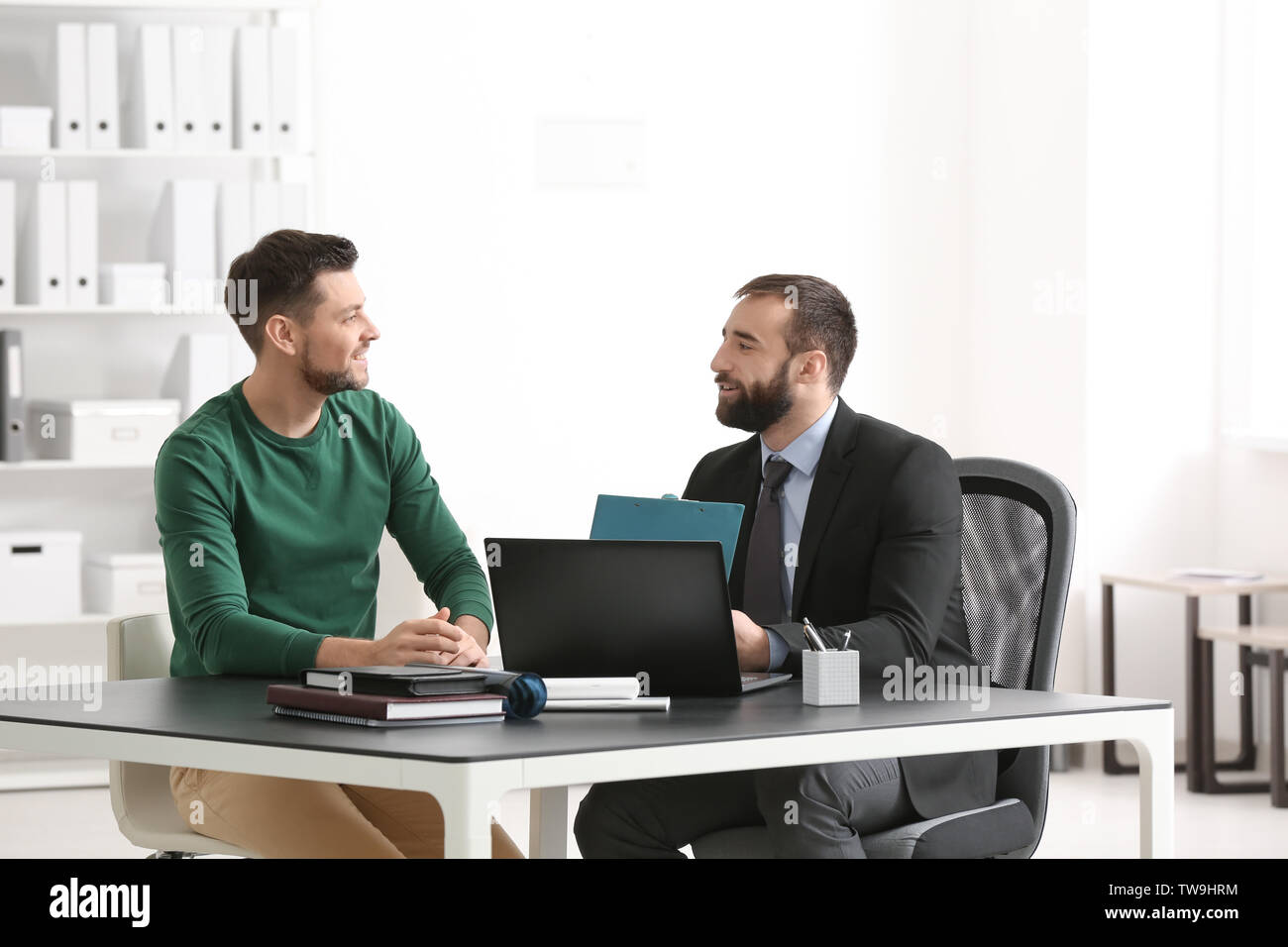 Businessman consulting young man in office Stock Photo - Alamy